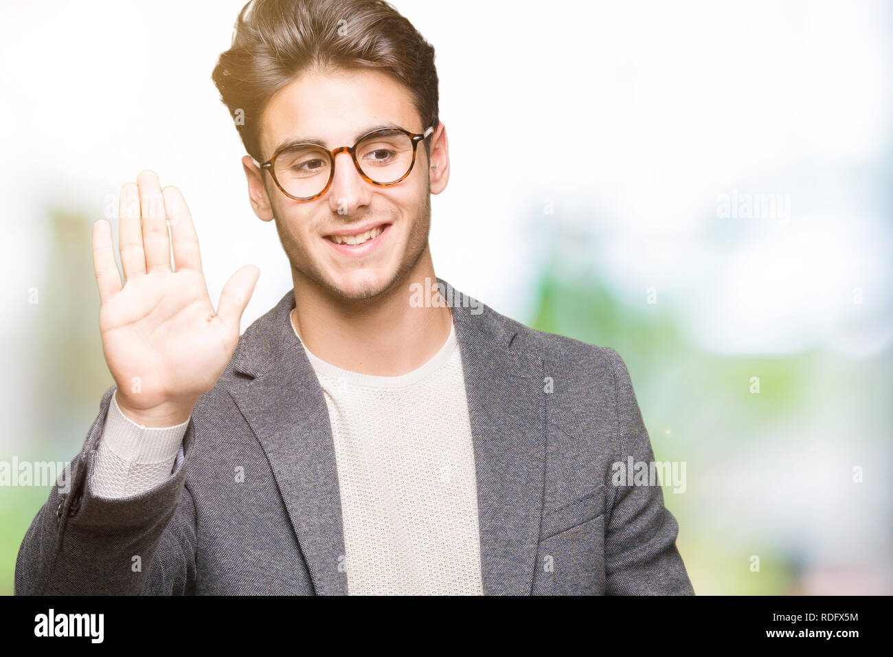 Young business man wearing glasses over isolated background Waiving ...