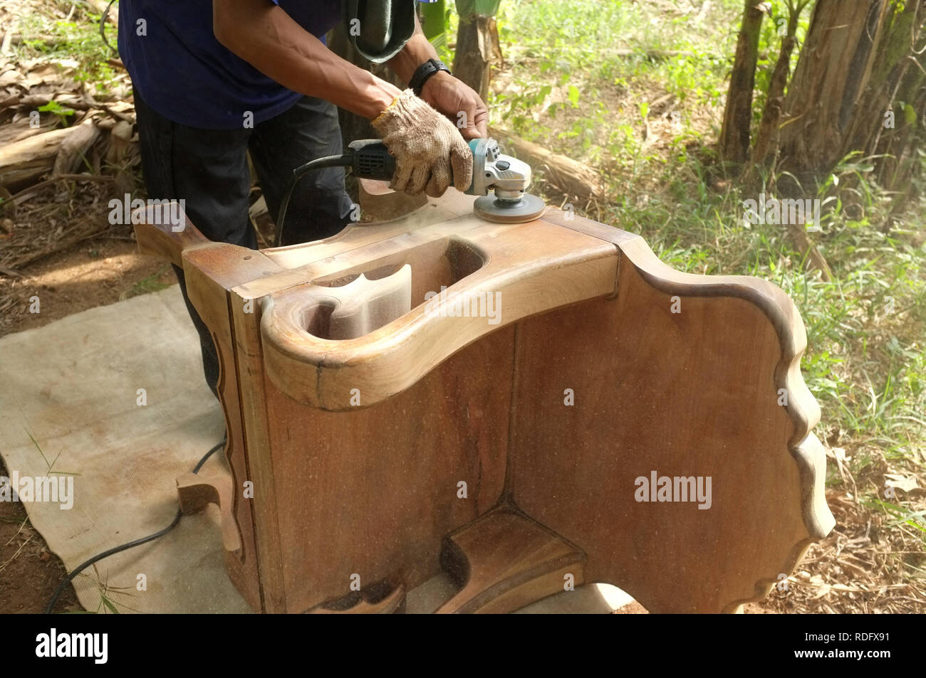 Close up of a carpenter scrubbing wood chair with handheld electric ...