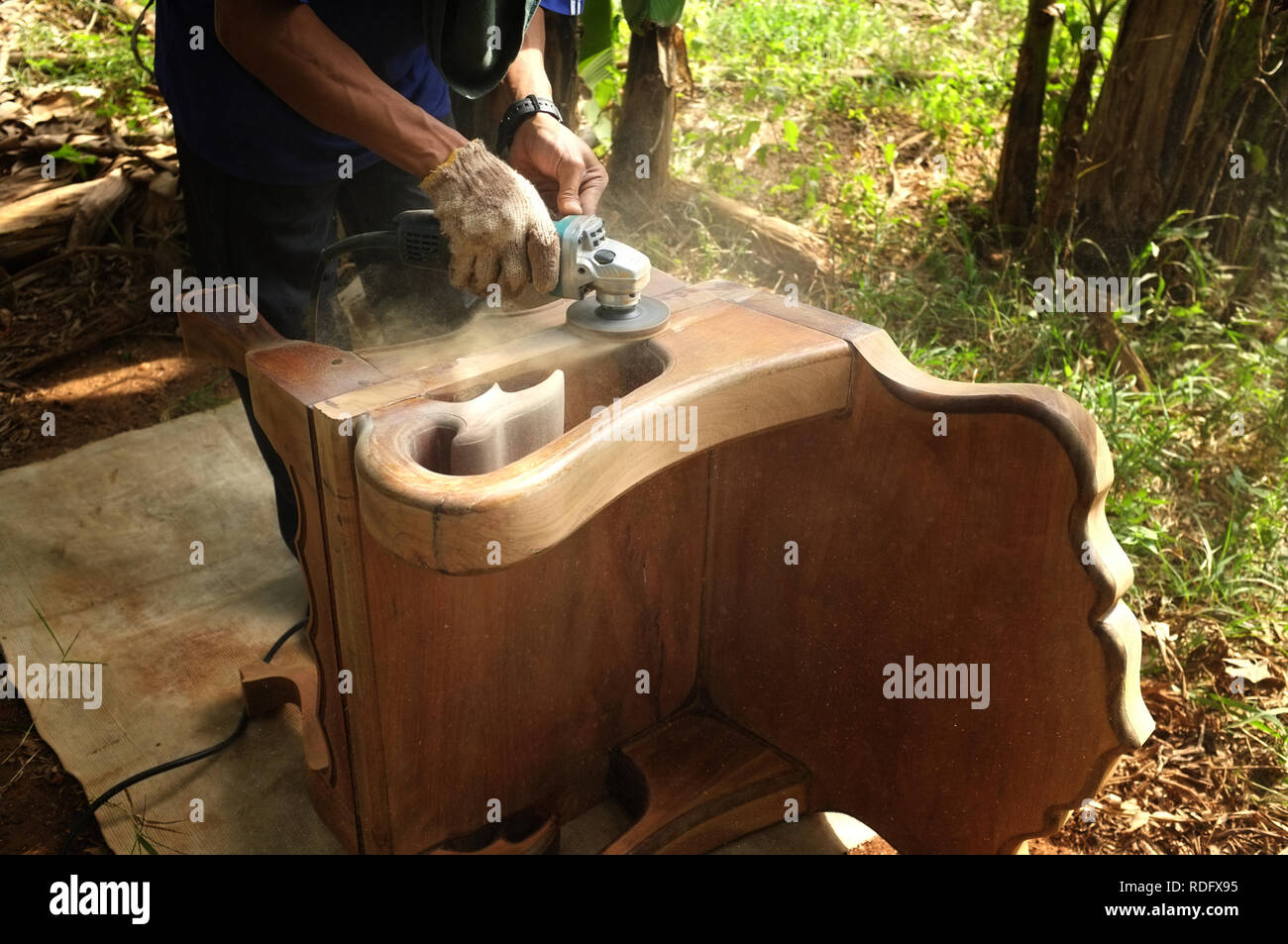 Close up of a carpenter scrubbing wood chair with handheld electric ...