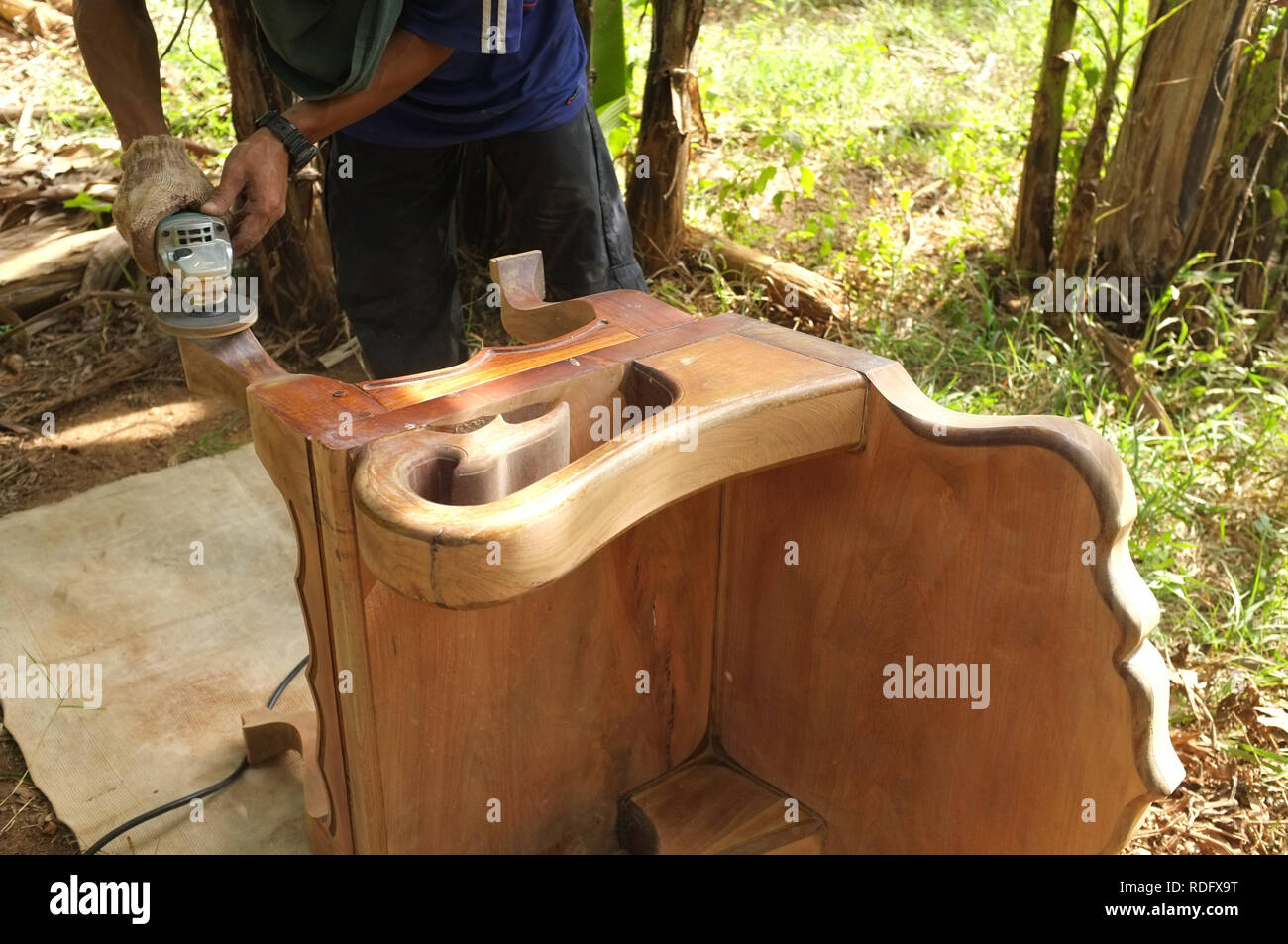 Close up of a carpenter scrubbing wood chair with handheld electric ...