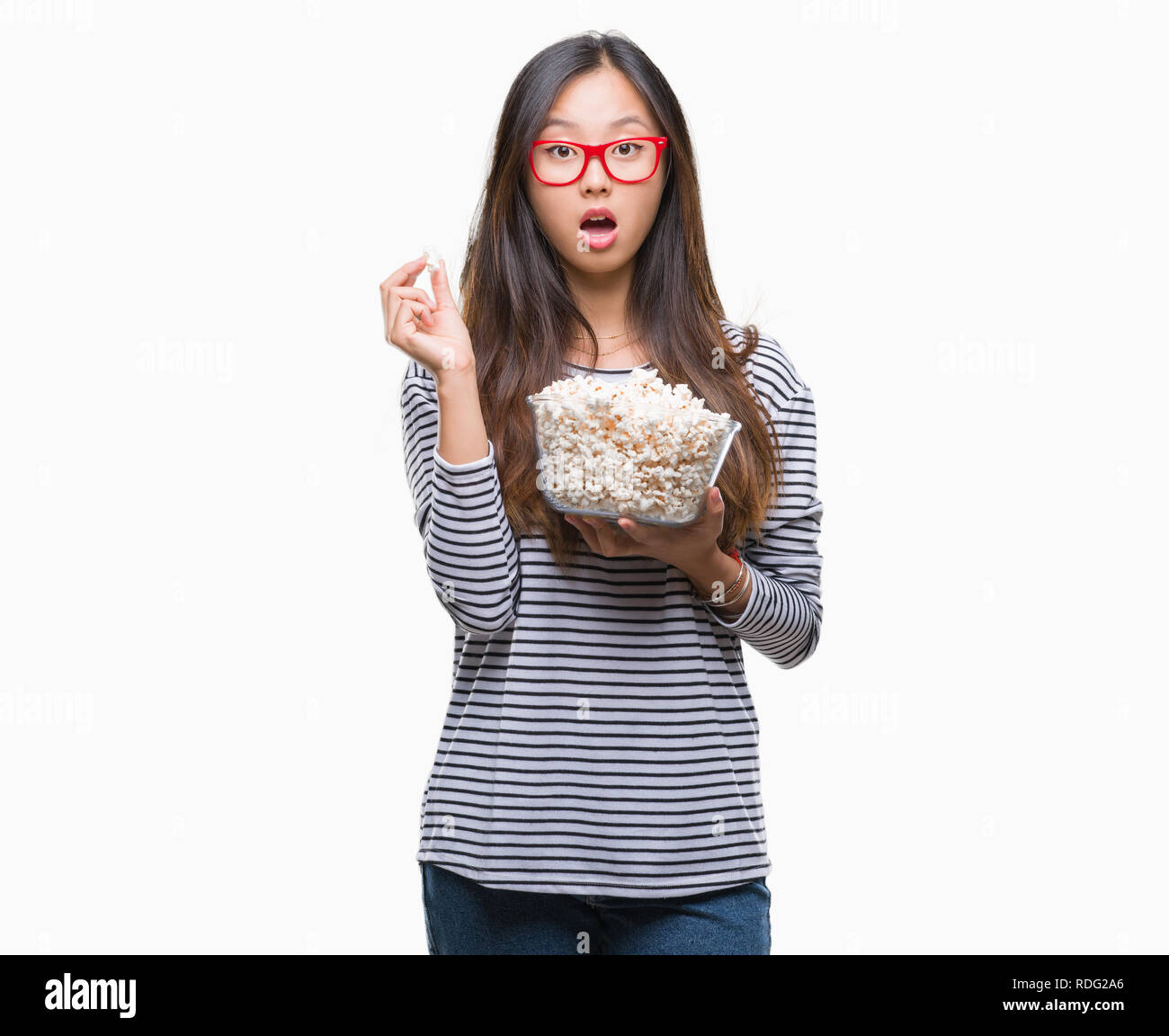 Young asian woman eating popcorn over isolated background scared in ...
