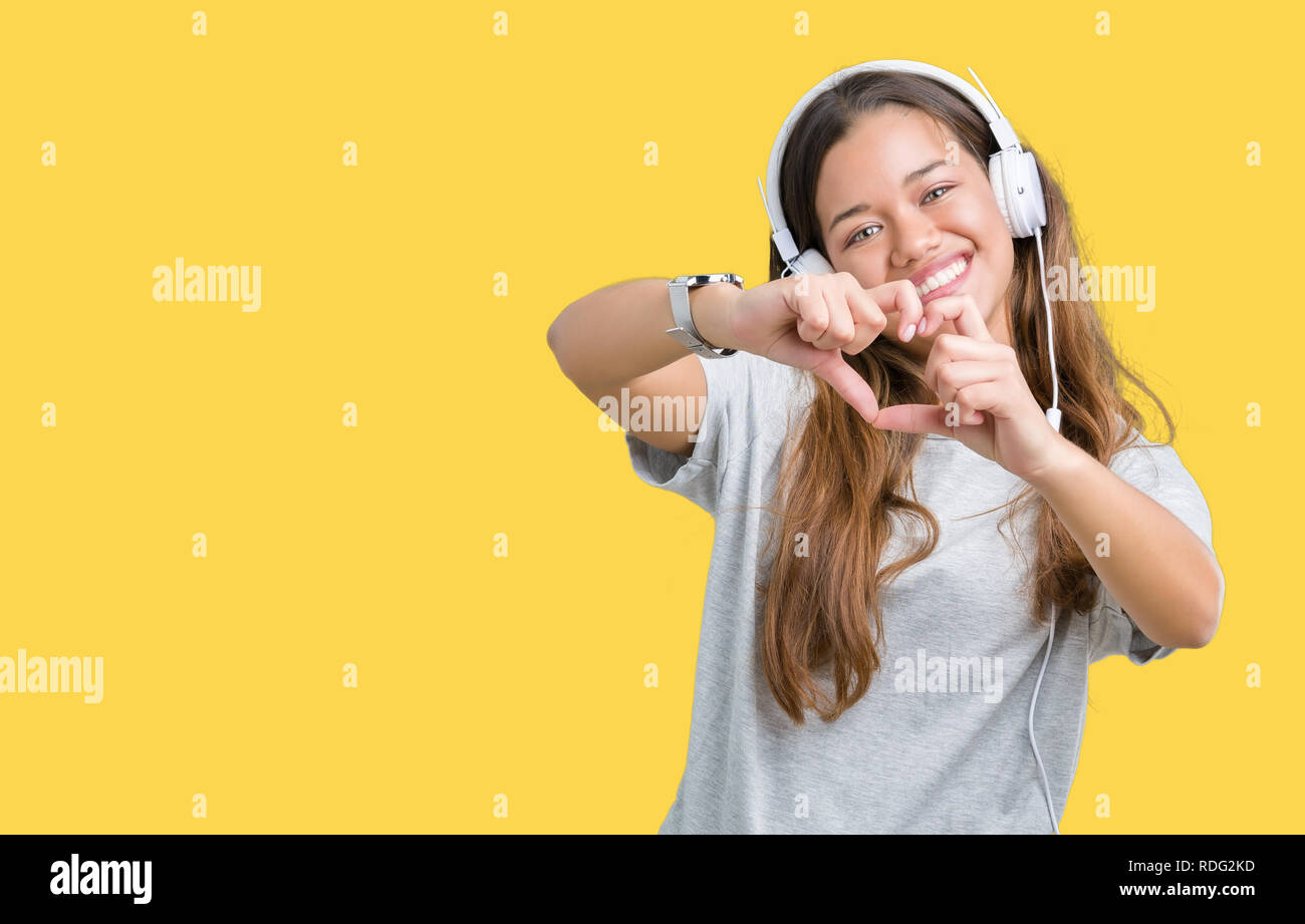 Young beautiful woman wearing headphones listening to music over ...