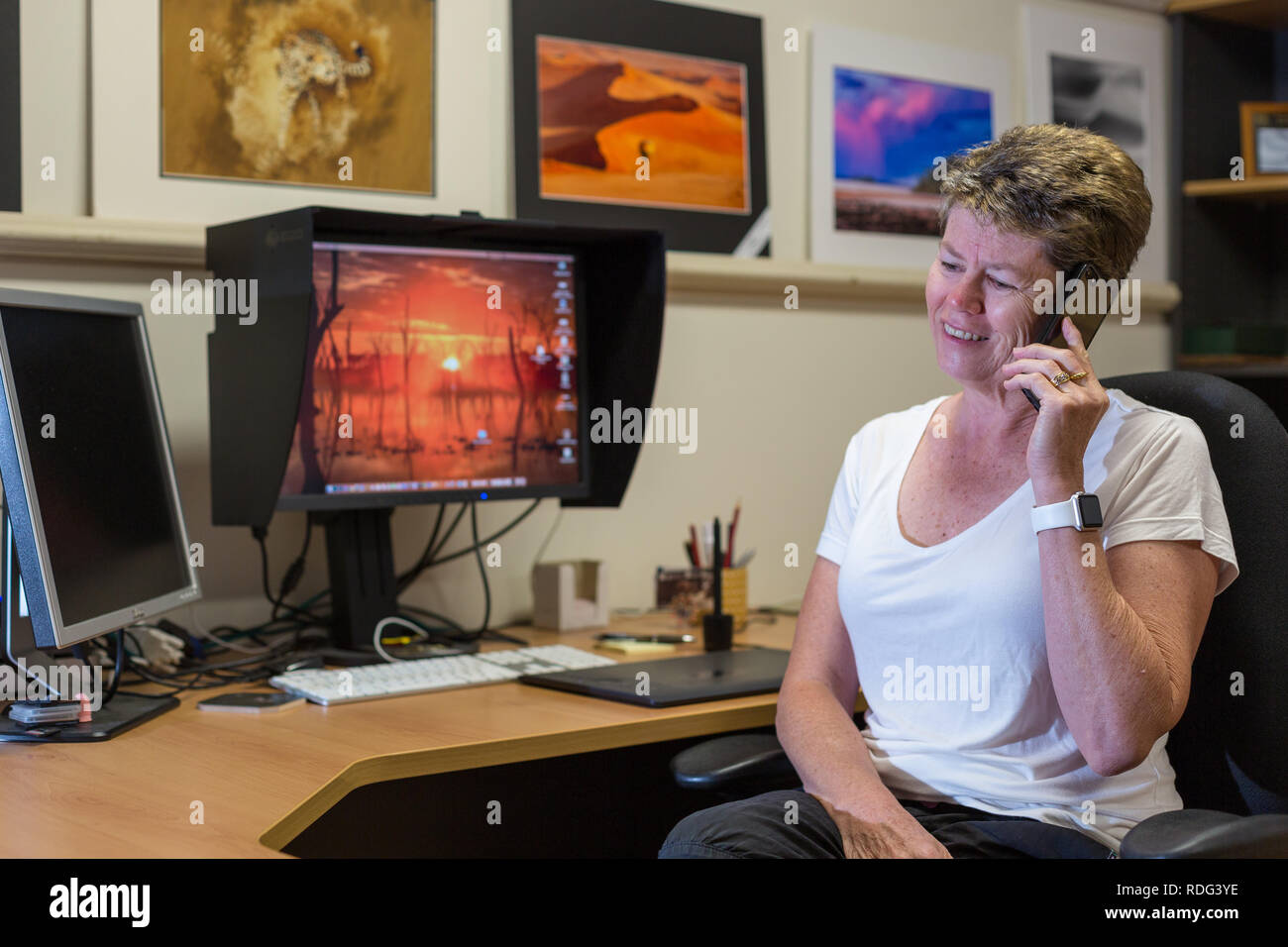 Lady in home office smiling while on mobile phone Stock Photo - Alamy