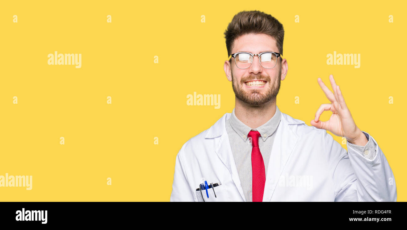 Young handsome scientist man wearing glasses smiling positive doing ok ...