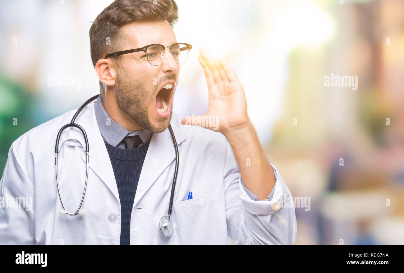 Young handsome doctor man over isolated background shouting and ...