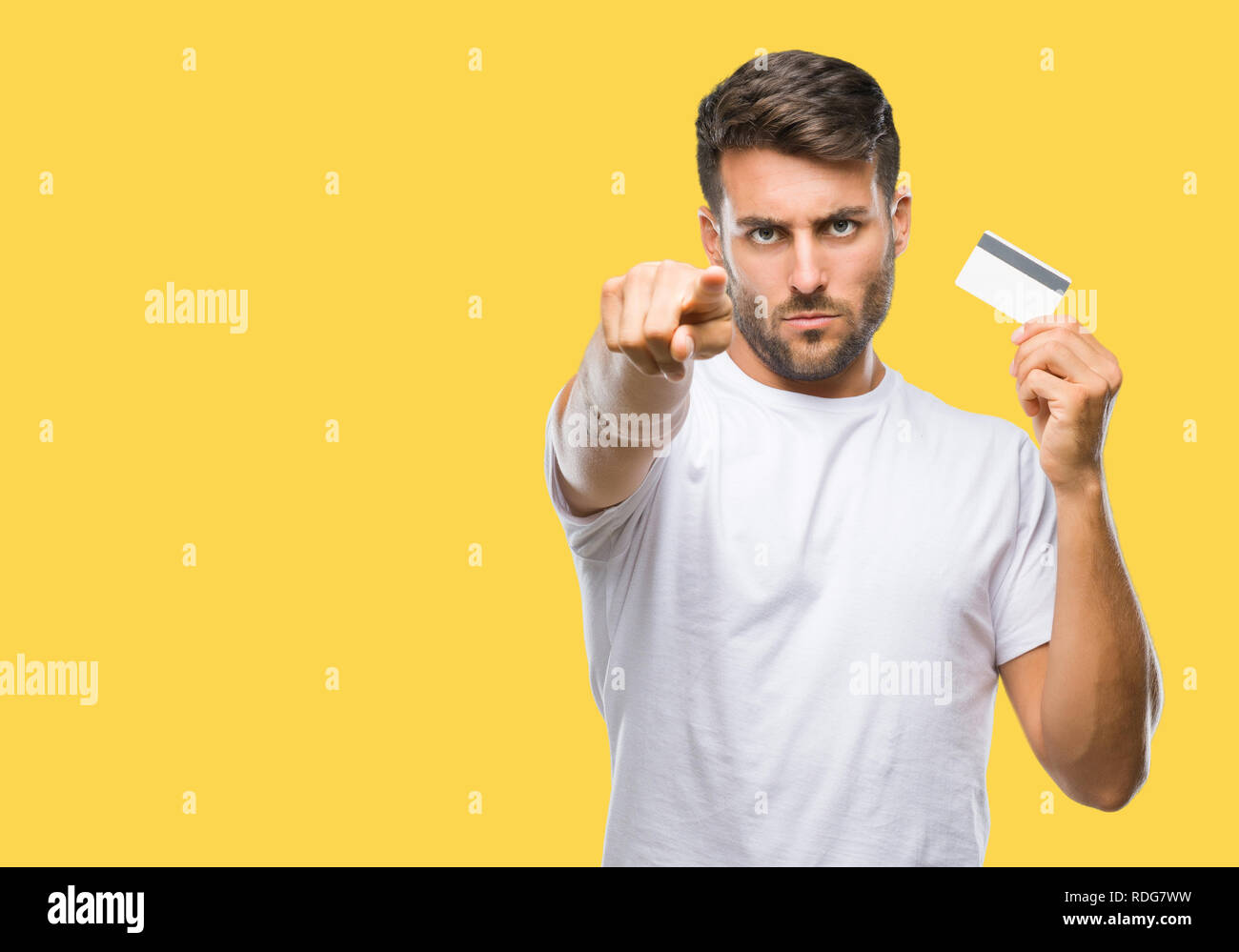 Young handsome man holding credit card over isolated background ...