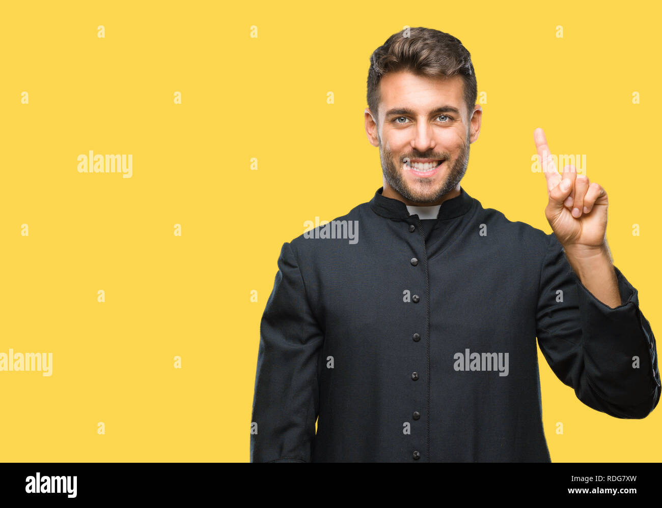 Young catholic christian priest man over isolated background showing ...