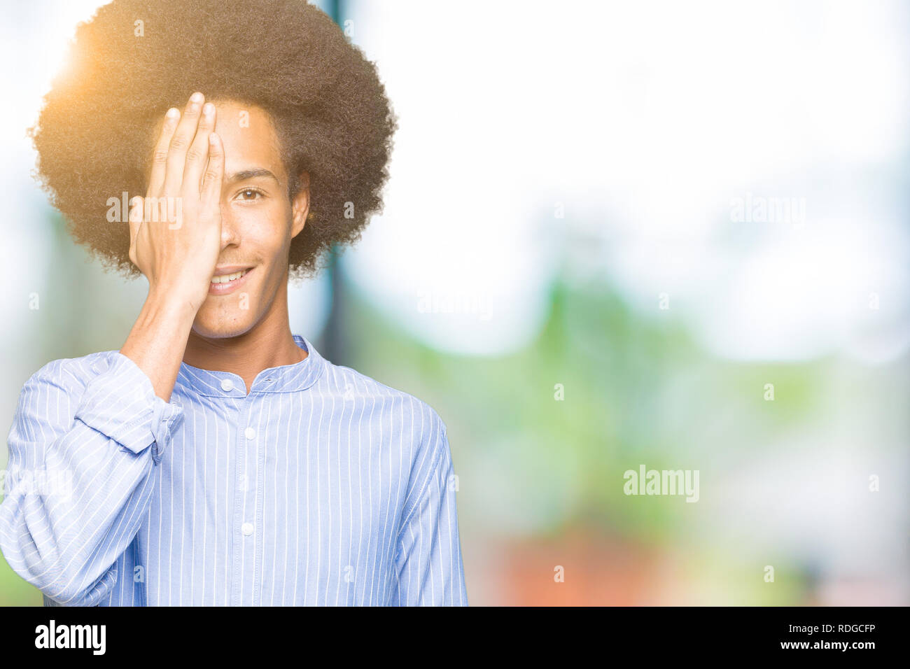 Young african american man with afro hair covering one eye with hand ...