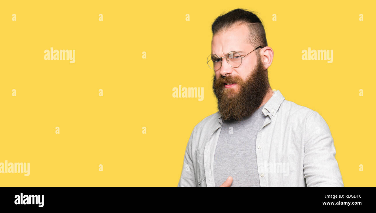 Young blond man wearing glasses disgusted expression, displeased and ...