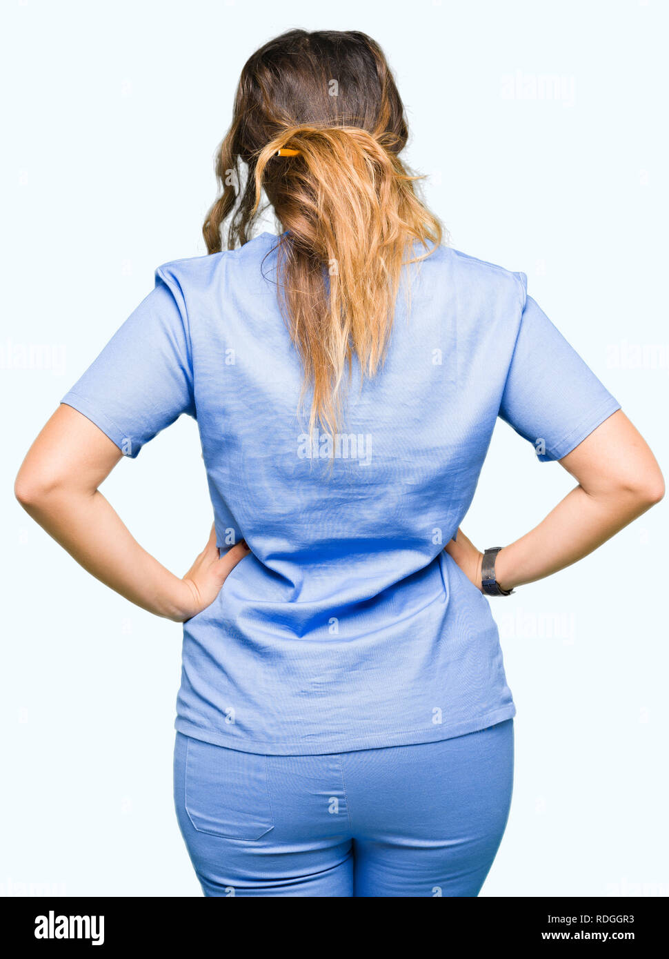 Young adult doctor woman wearing medical uniform standing backwards ...