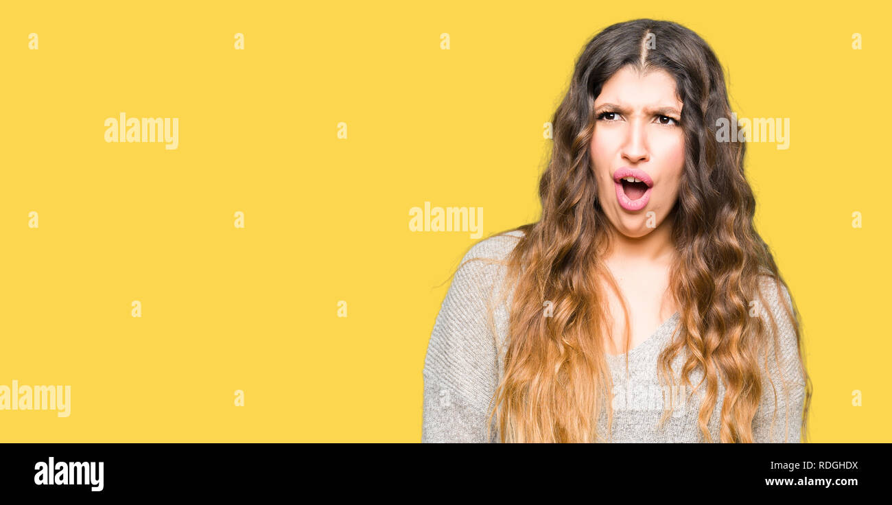 Young beautiful woman wearing winter dress In shock face, looking ...