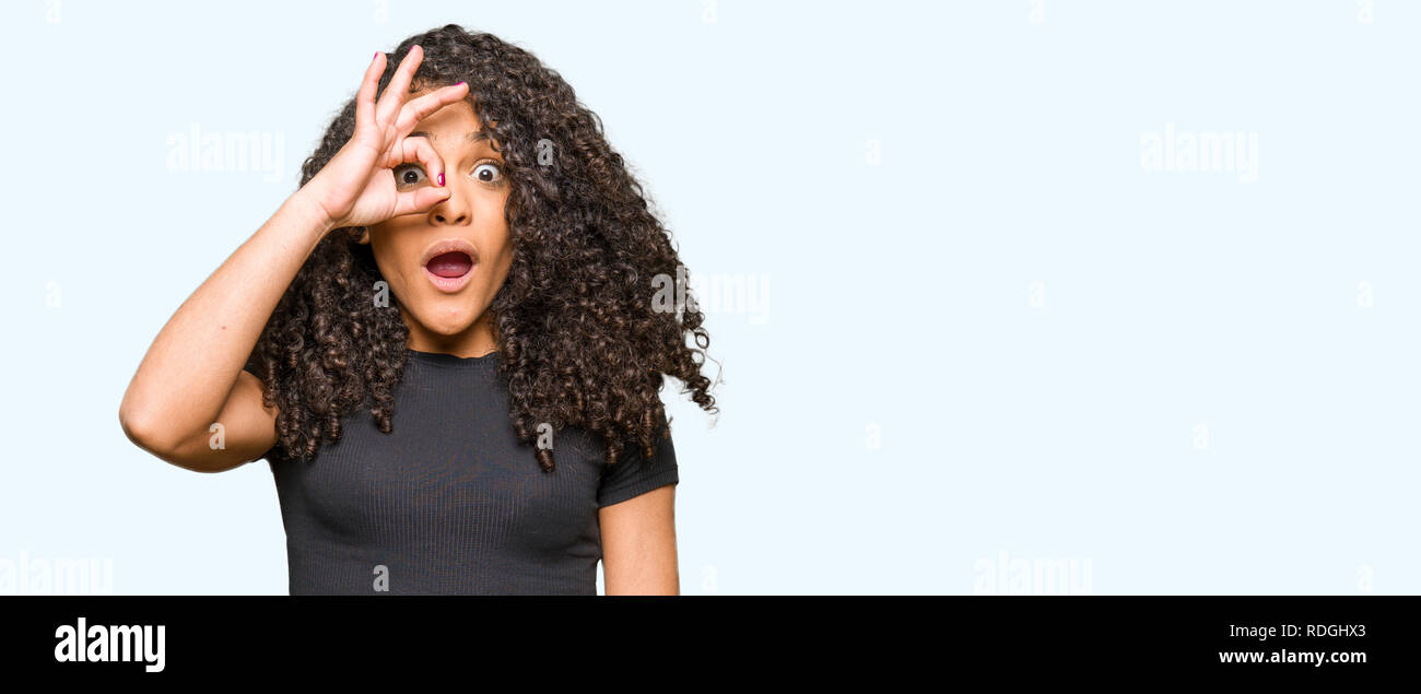 Young beautiful woman with curly hair doing ok gesture shocked with ...