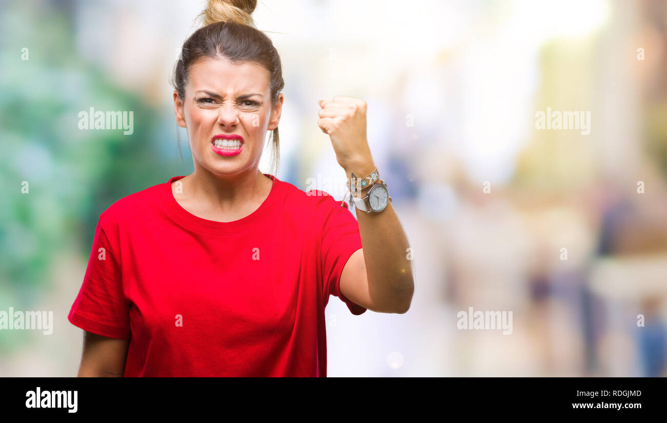 Young beautiful woman over isolated background angry and mad raising ...