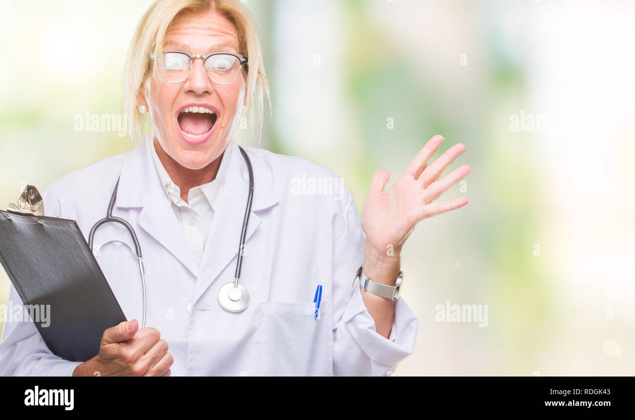 Middle age blonde doctor woman holding clipboard over isolated ...
