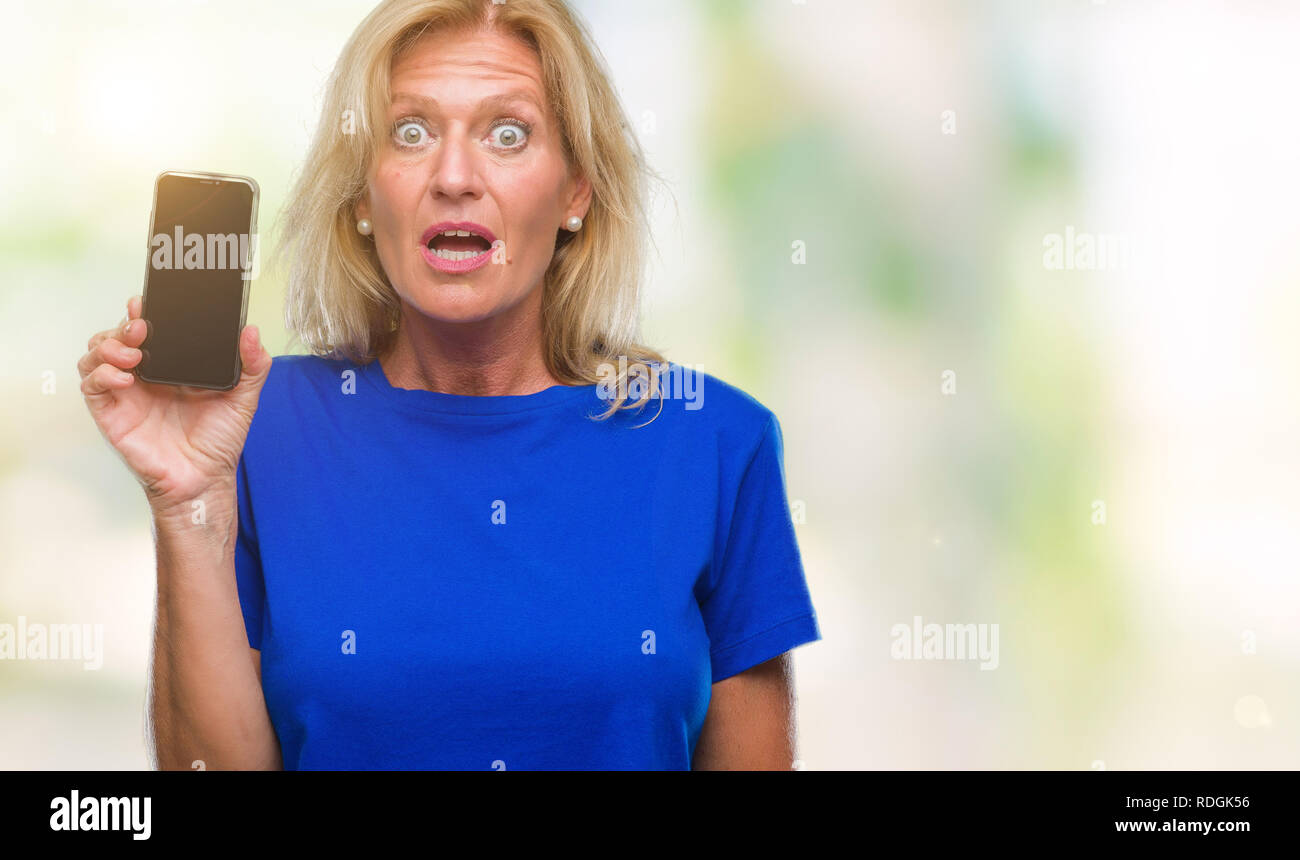 Middle age blonde woman showing blank screen of smartphone over ...