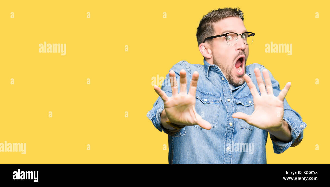 Handsome man wearing glasses afraid and terrified with fear expression ...