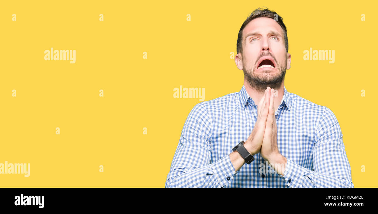 Handsome business man with blue eyes begging and praying with hands ...