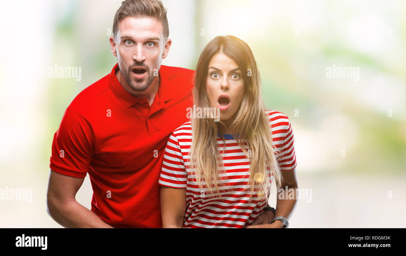 Young couple in love over isolated background afraid and shocked with ...