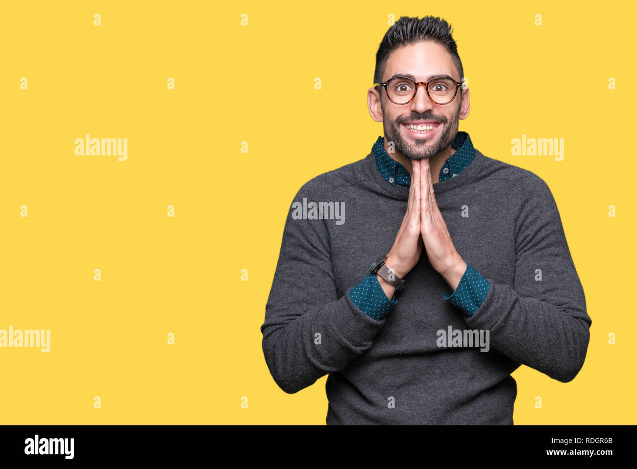 Young handsome man wearing glasses over isolated background praying ...