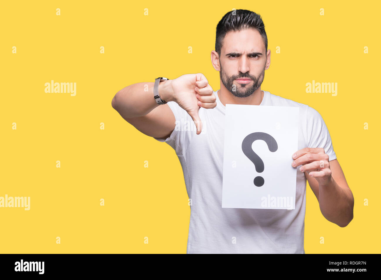 Handsome young man holding paper with question mark over isolated ...