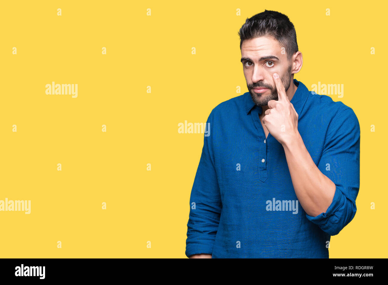 Young handsome man over isolated background Pointing to the eye ...