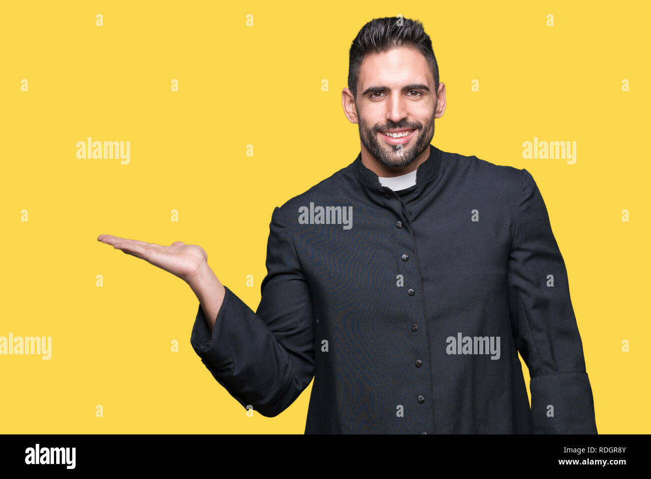 Young Christian priest over isolated background smiling cheerful ...