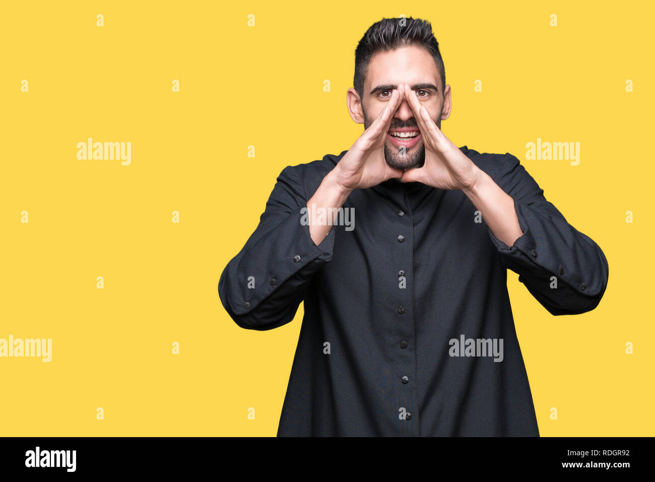 Young Christian priest over isolated background Shouting angry out loud ...