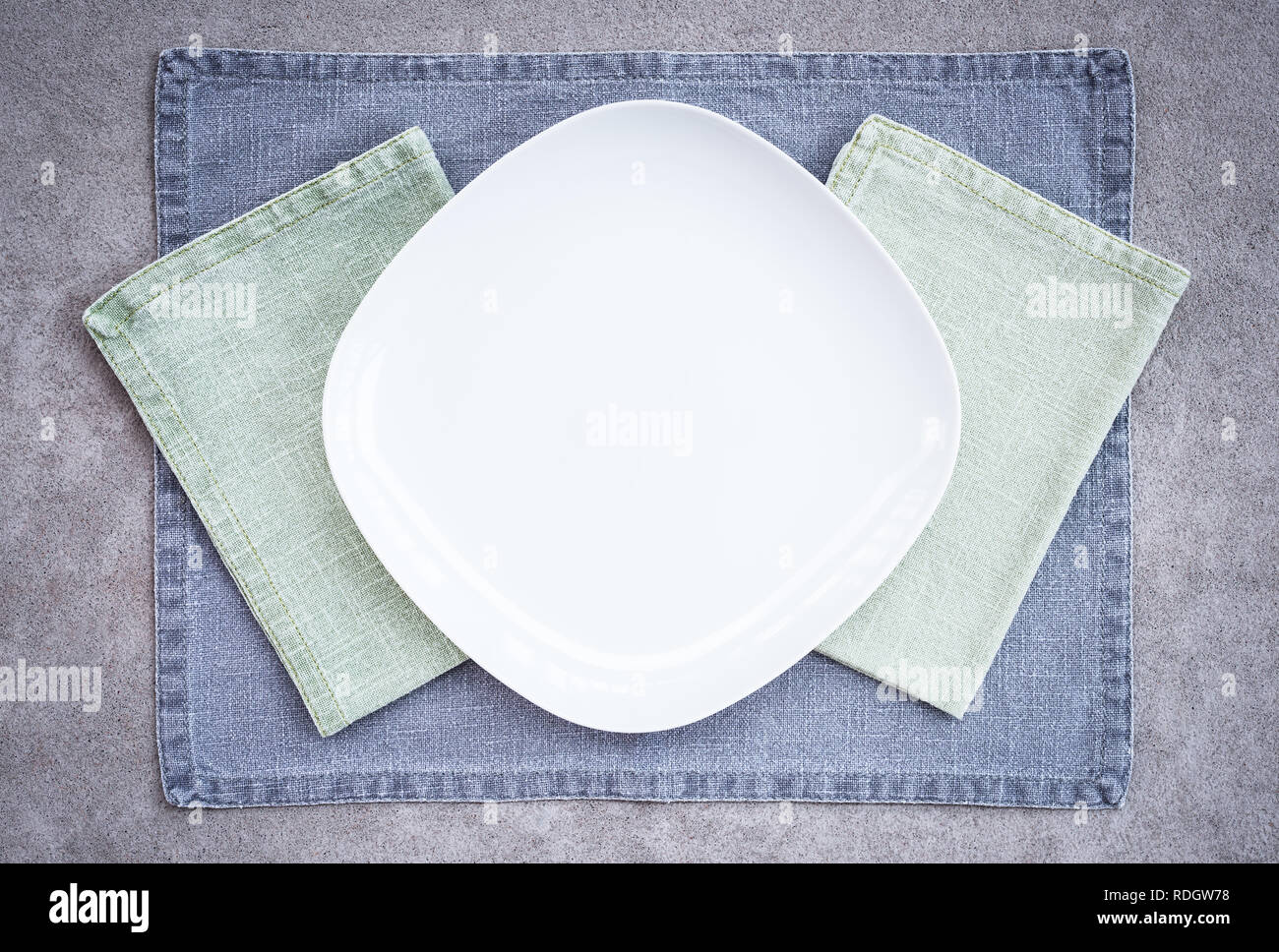 White plate and simple linen textiles on concrete background. Pastel ...