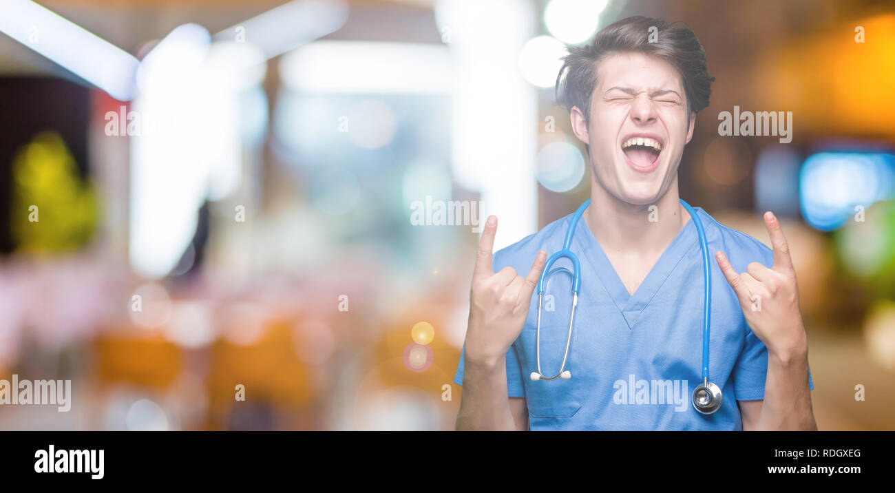 Young doctor wearing medical uniform over isolated background shouting ...