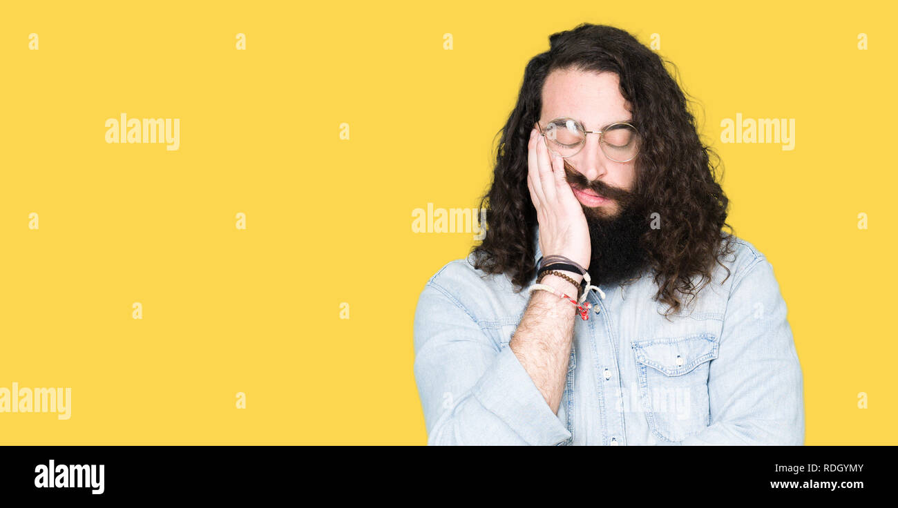 Young hipster man with long hair and beard wearing glasses thinking ...