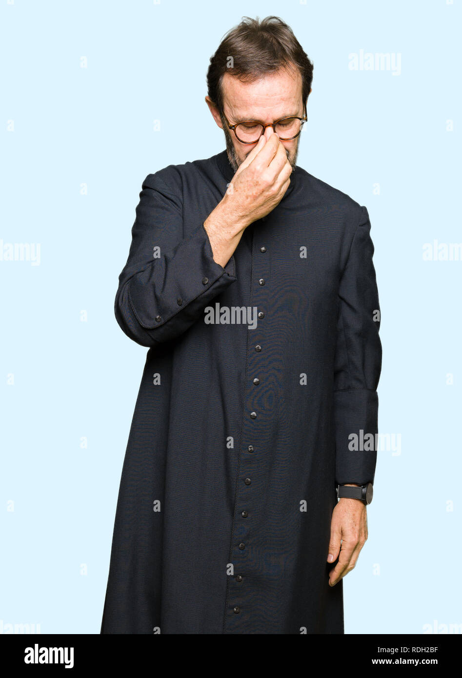 Middle age priest man wearing catholic robe tired rubbing nose and eyes ...