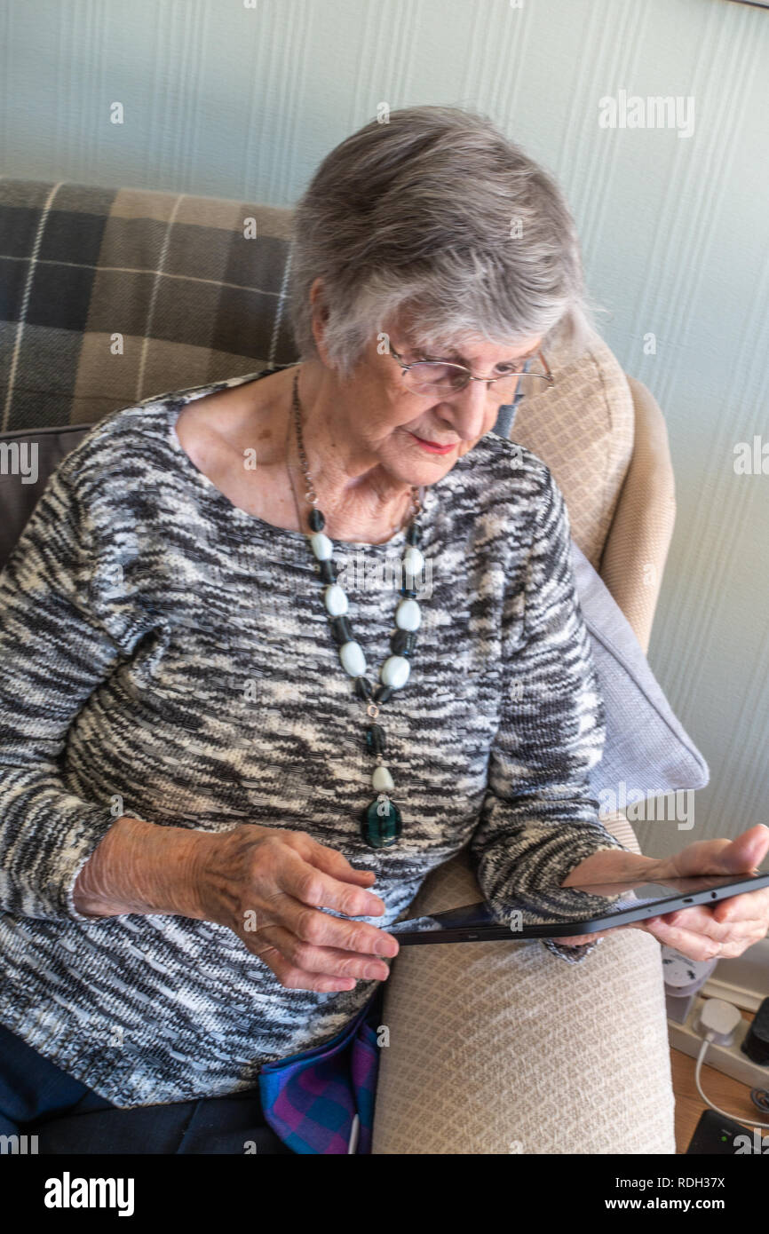 Elderly lady sitting using her personal tablet Stock Photo - Alamy