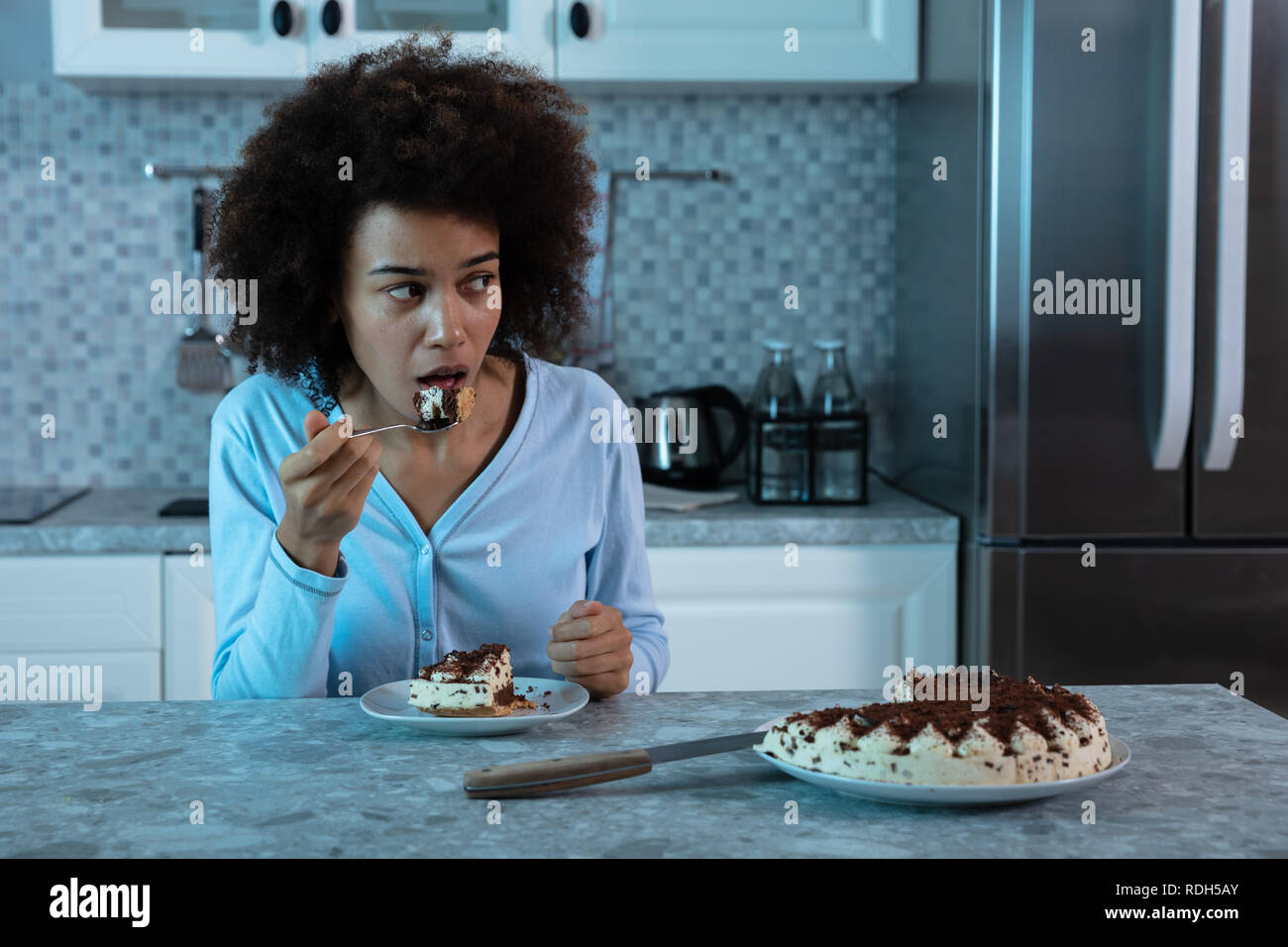Young African Woman Eating A Piece Of Cake With Spoon Sitting In The ...