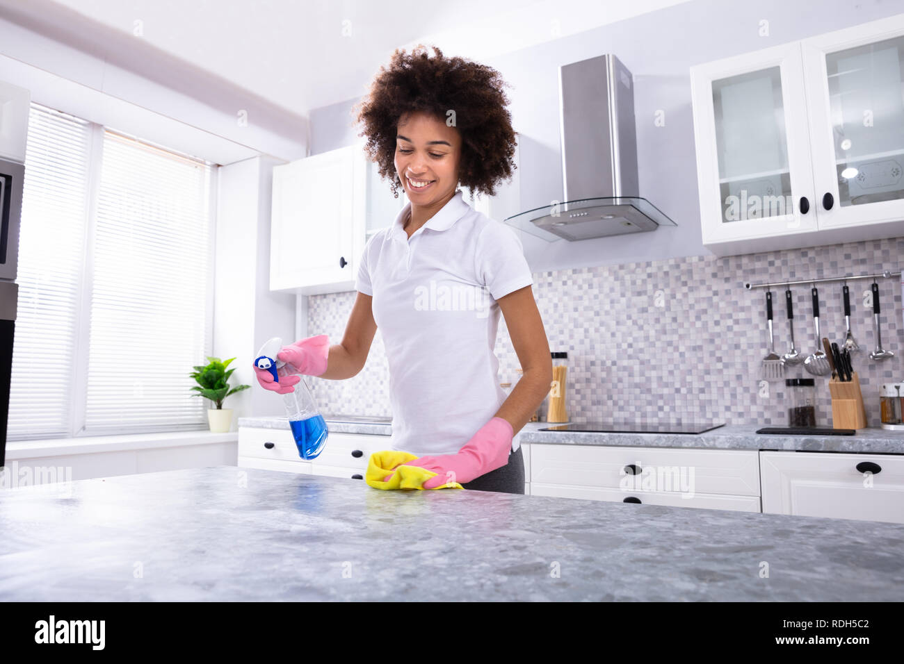Happy African Young Woman Cleaning Dirty Kitchen Counter With Spray ...