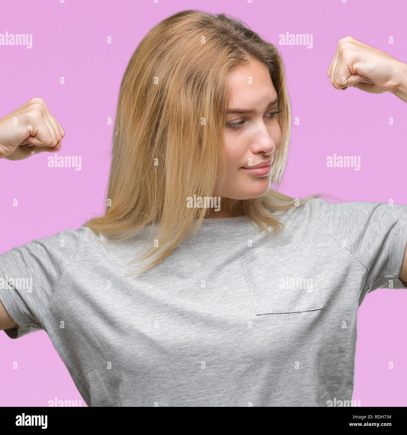 Young caucasian woman over isolated background showing arms muscles ...