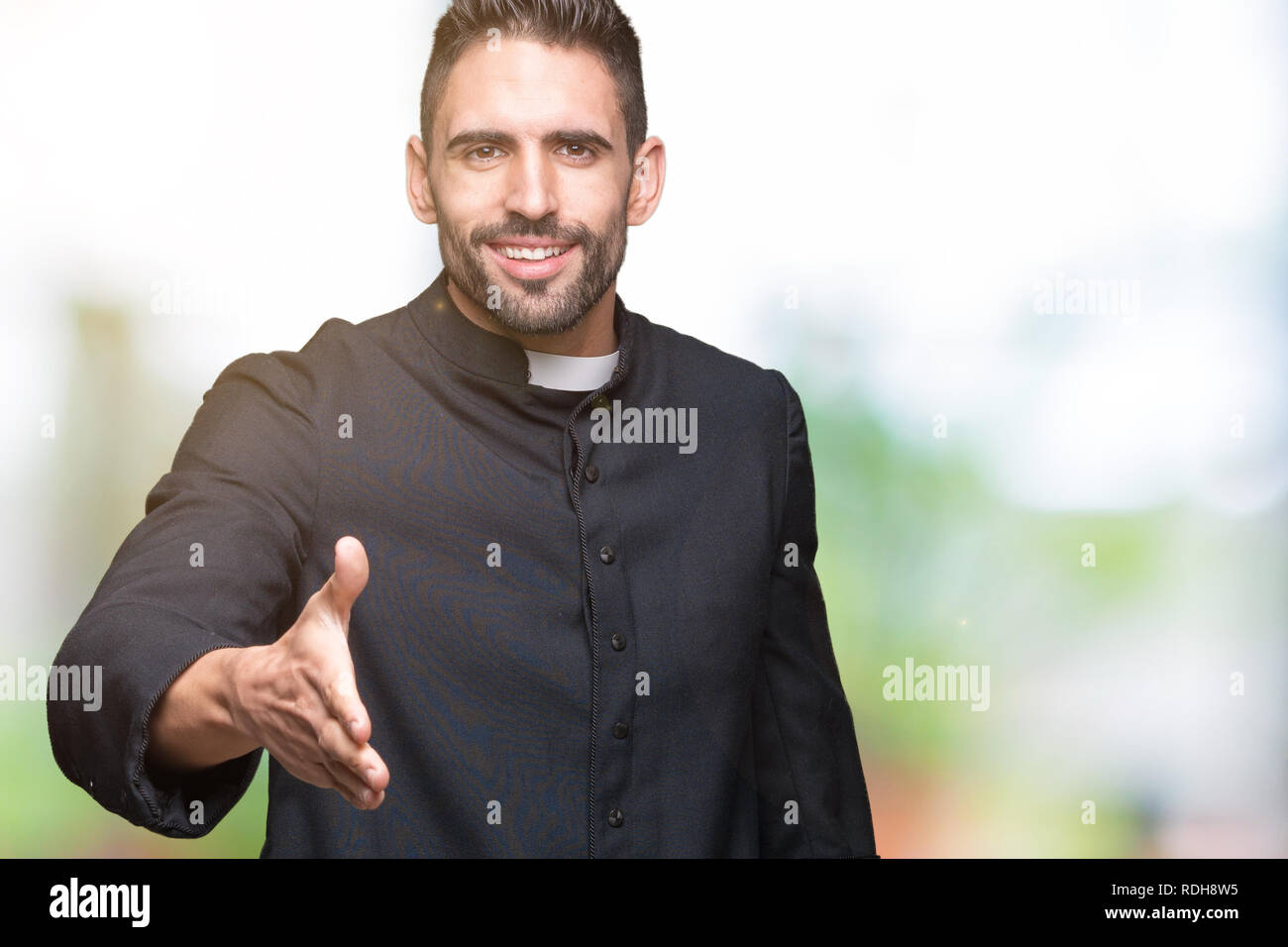 Young Christian priest over isolated background smiling friendly ...