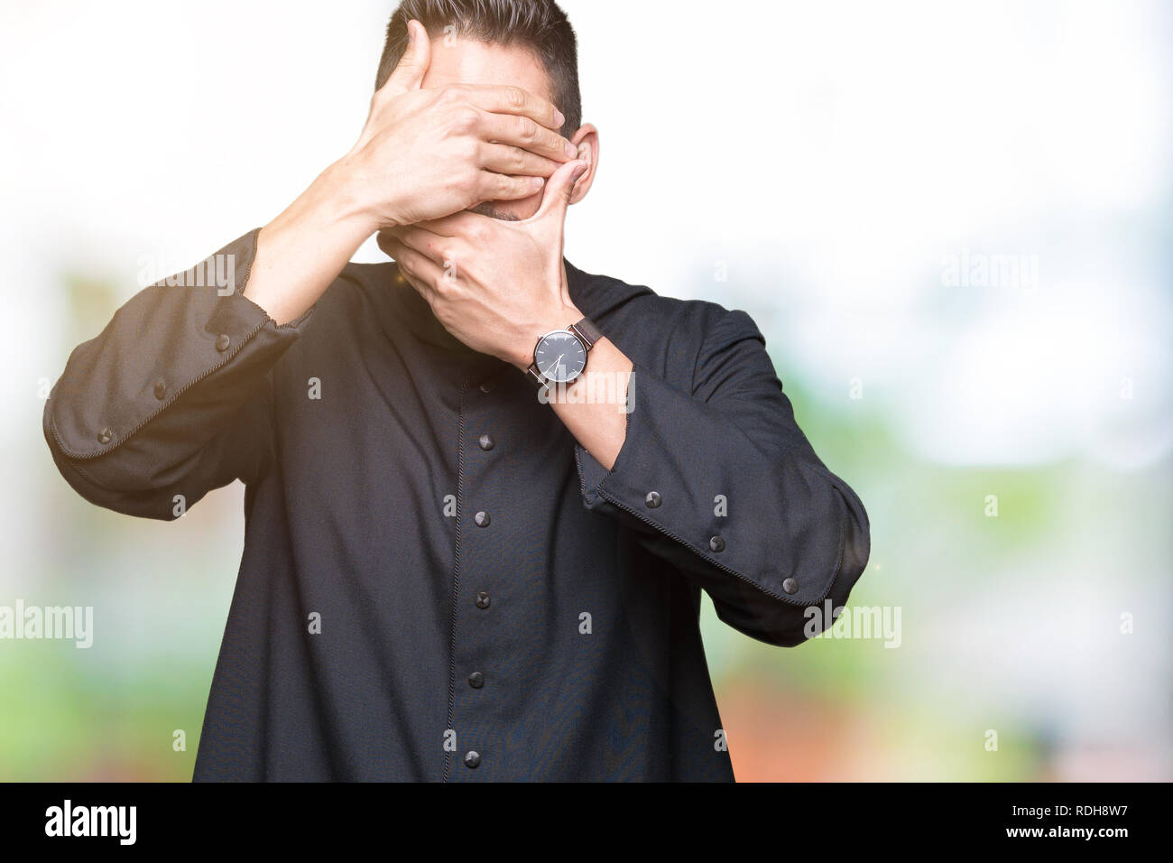 Young Christian priest over isolated background Covering eyes and mouth ...