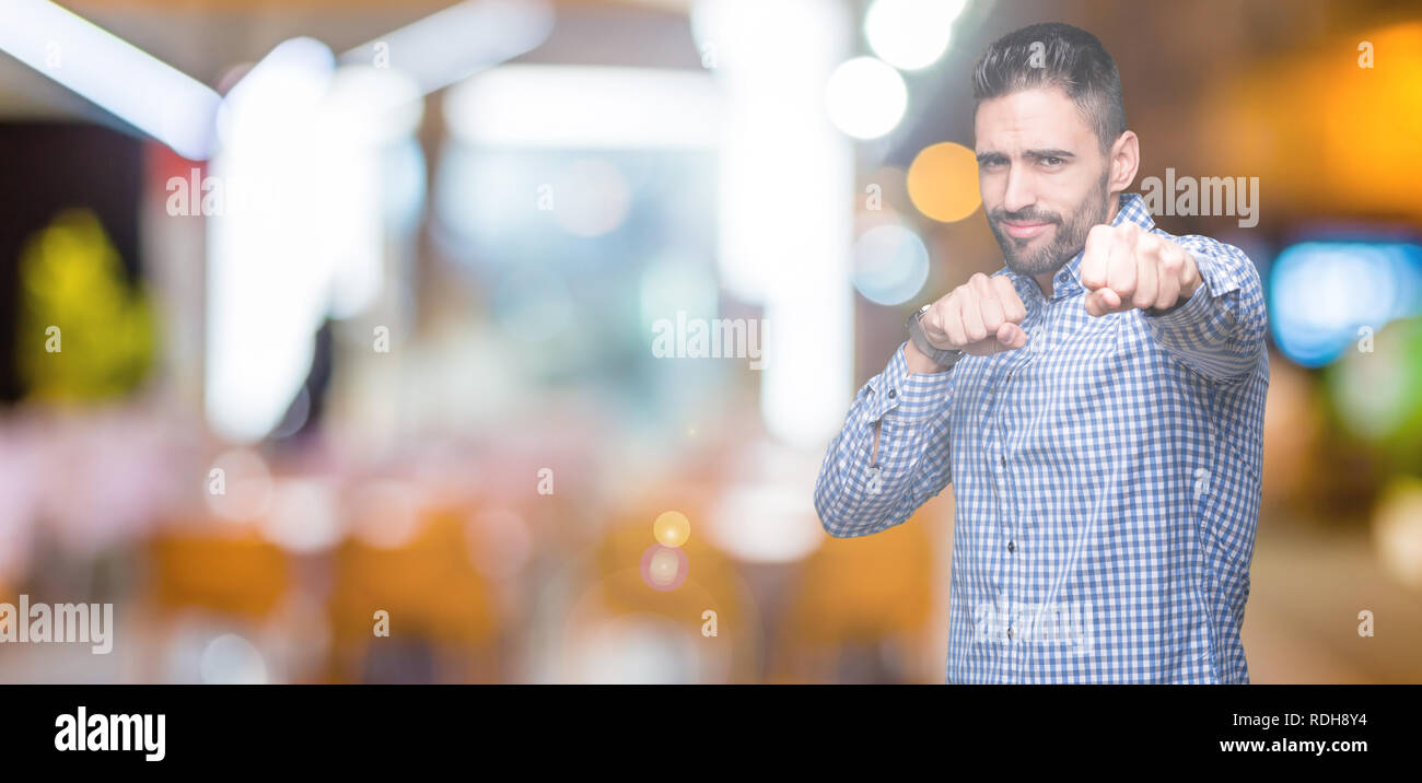 Young handsome man over isolated background Punching fist to fight ...