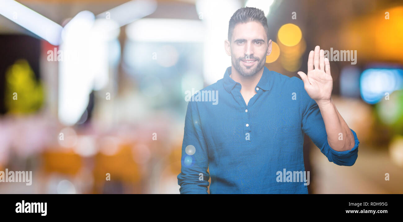 Young handsome man over isolated background Waiving saying hello happy ...