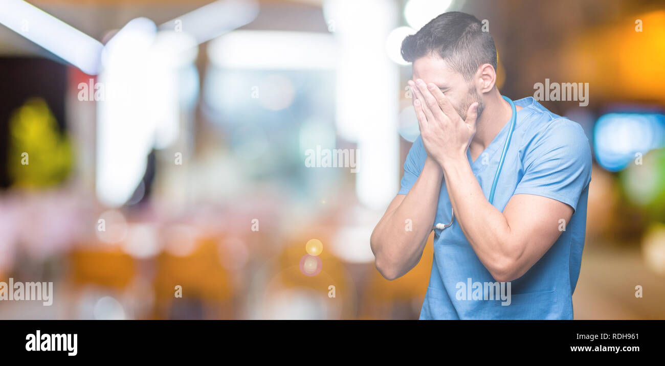 Handsome young doctor surgeon man over isolated background with sad ...