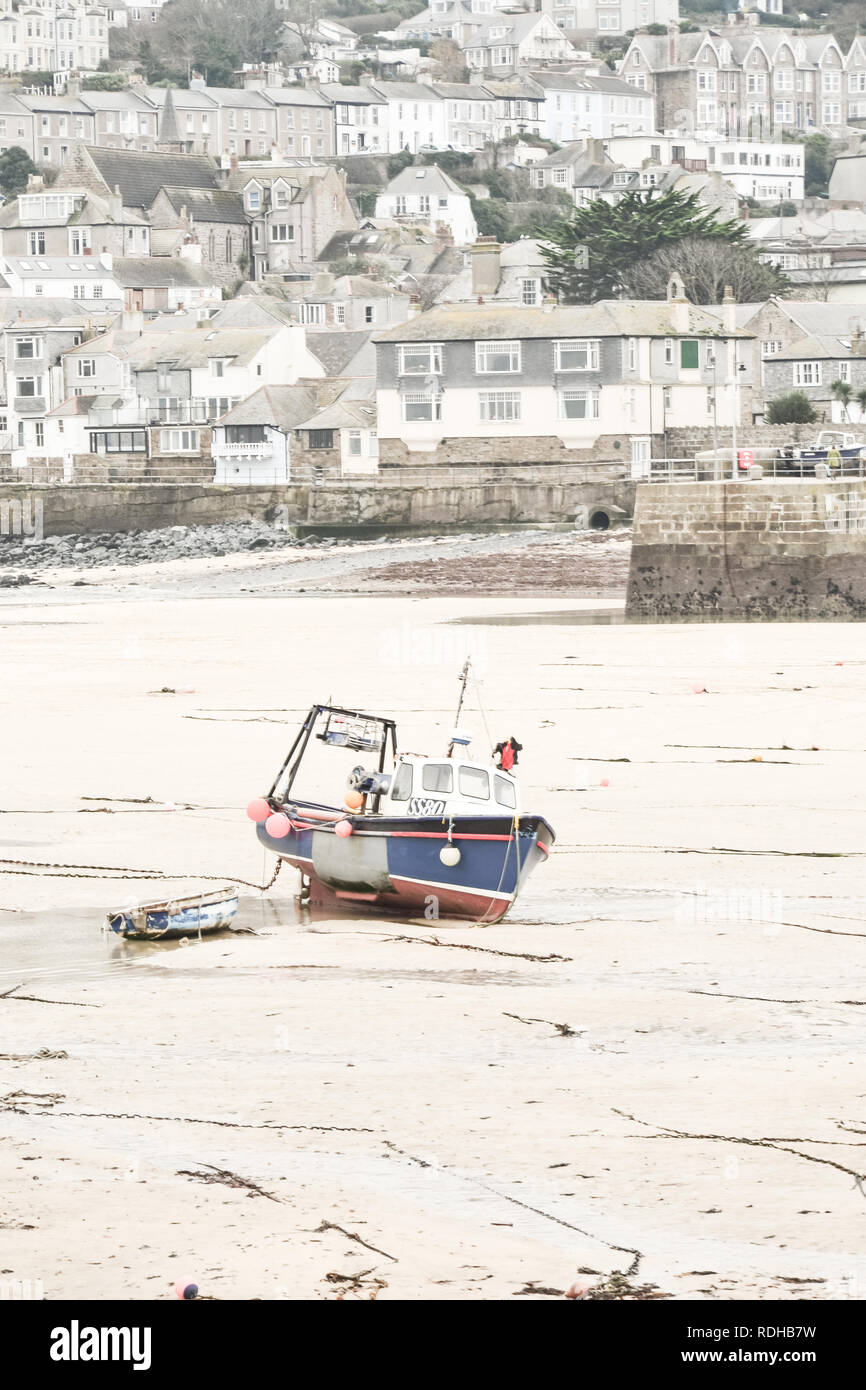 Low tide in the little protected harbour leaves the boats stranded on ...