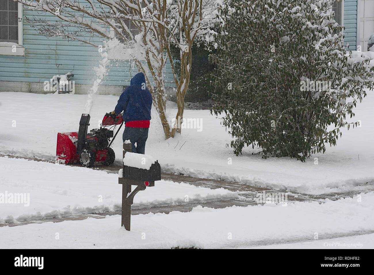 Adult male using red snow blower on sidewalk Stock Photo - Alamy