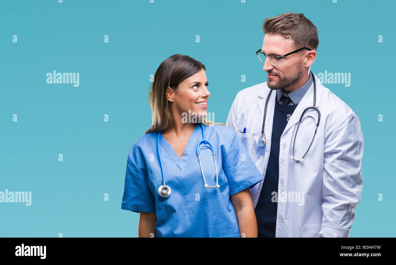 Young couple of doctor and surgeon over isolated background looking ...