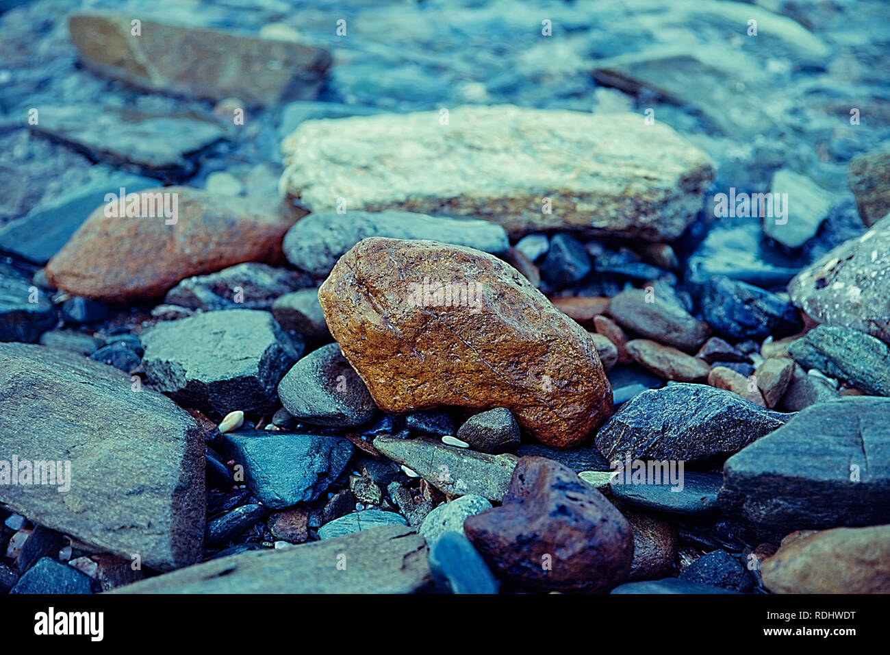 Seaside stones on beach shot with a blue filter. Sharpness in the ...