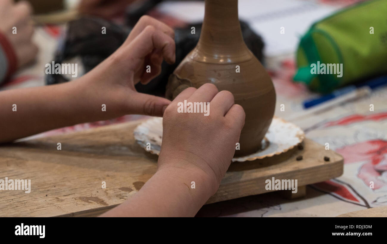 child in the process of decorating the clay pot. children's pottery ...
