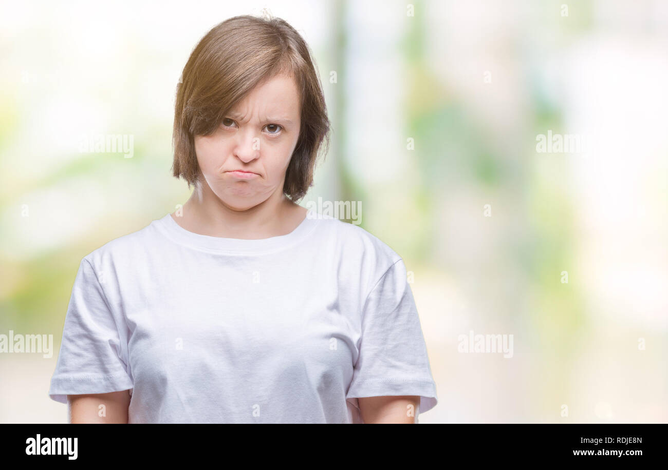 Young adult woman with down syndrome over isolated background depressed ...