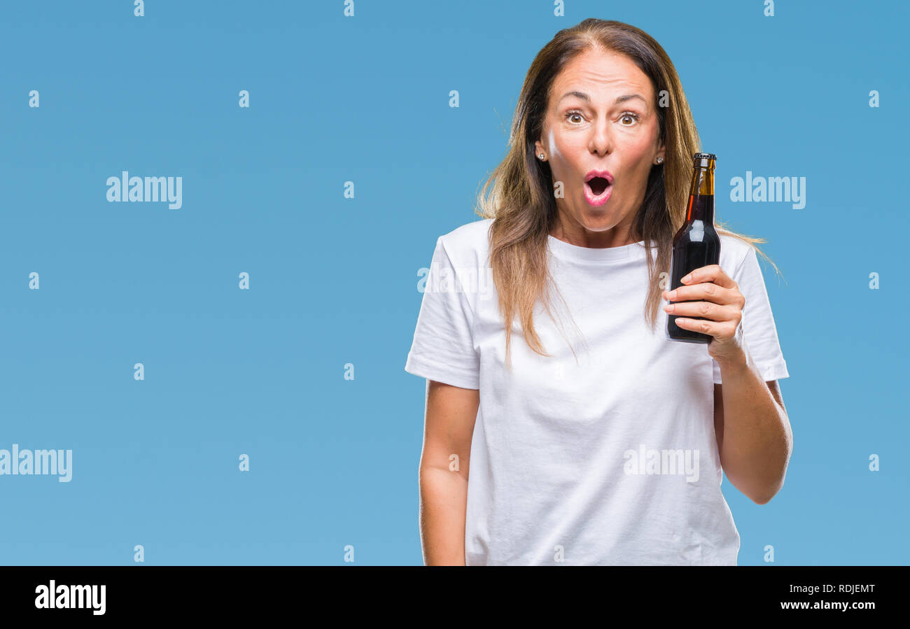 Middle age hispanic woman drinking beer over isolated background scared ...
