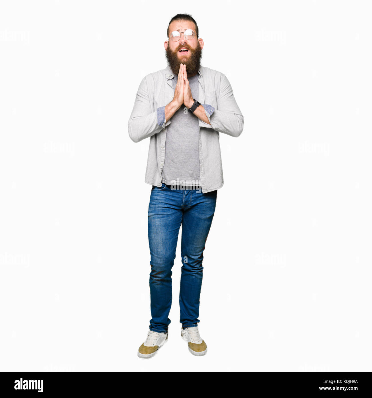 Young blond man wearing glasses begging and praying with hands together ...