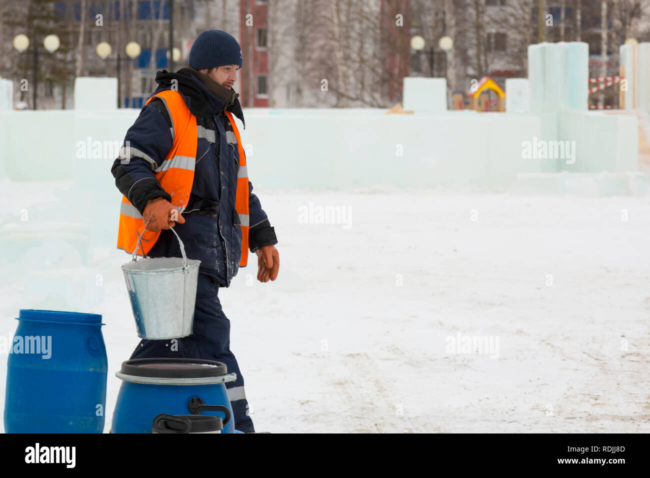 Worker with a bucket in hand at the assembly site of the ice town Stock ...