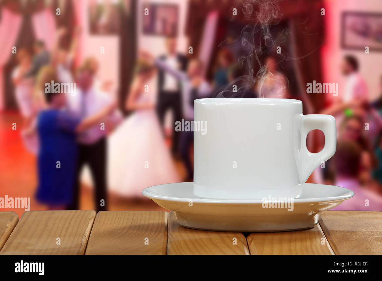 Dancing people at a party against a cup of coffee or tea and empty ...